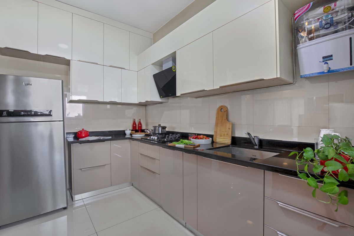 L-Shape Modular Beige And Champagne Kitchen Design With Black Kitchen Countertop | Livspace